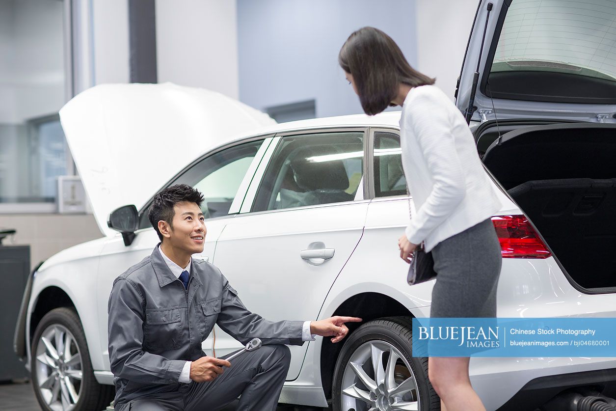 Chinese auto mechanic talking with car owner-High-res stock photo for download
