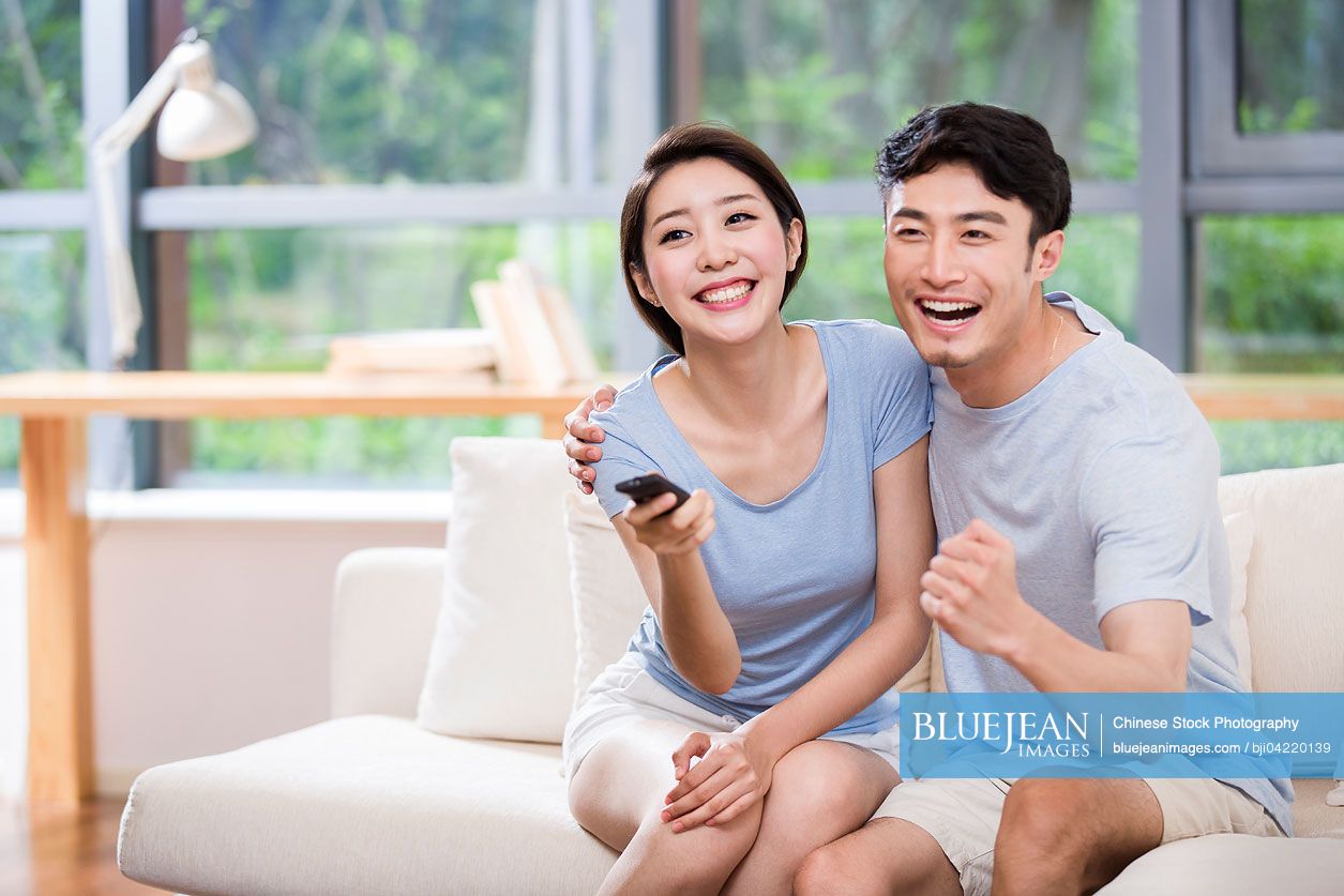 Young Chinese couple changing channels-High-res stock photo for download