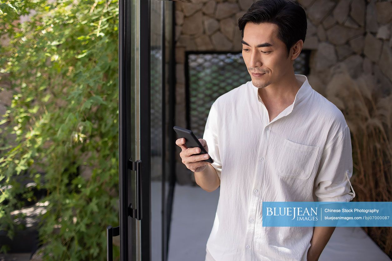 Happy mid adult Chinese man using smart phone-High-res stock photo for ...