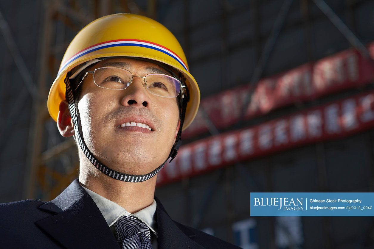 Chinese businessman wearing hard hat in construction site-High-res ...