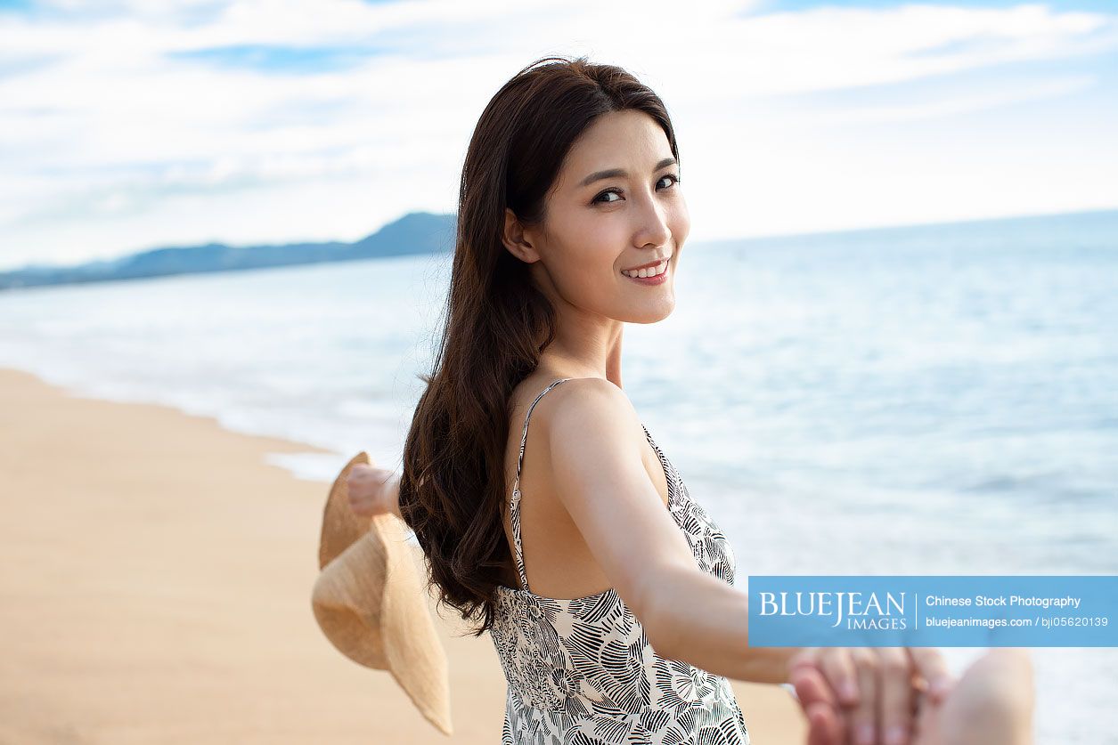 Cropped image of young Chinese couple holding hands on beach-High-res stock photo for download