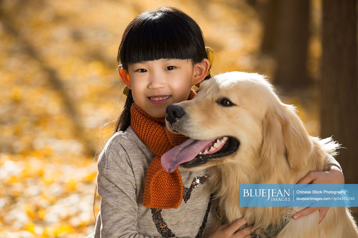 Little Chinese girl playing with dog in autumn woods-High-res stock ...