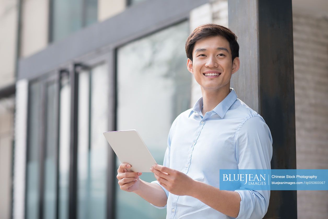 Young Chinese businessman holding a digital tablet outdoors-High-res ...