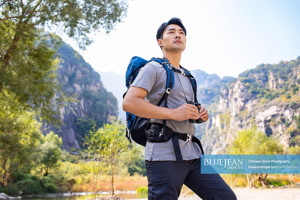 Young Chinese man hiking outdoors-High-res stock photo for download