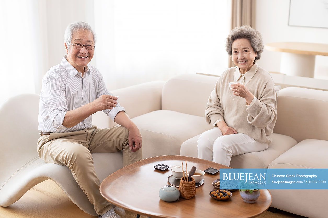 Cheerful senior Chinese couple drinking tea at home-High-res stock photo for download