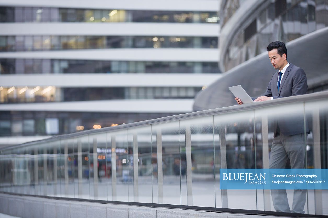 Chinese businessman using laptop outdoors-High-res stock photo for download