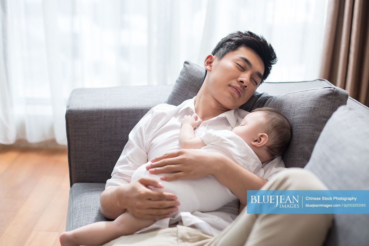 Young Chinese father and baby boy sleeping on sofa-High-res stock photo ...