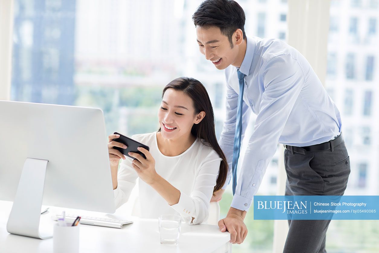 Young Chinese business people playing mobile game in office-High-res ...