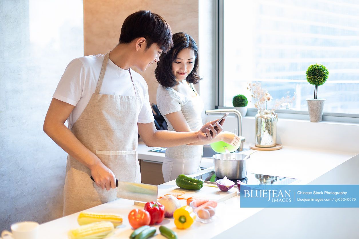 Happy young Chinese couple cooking in kitchen-High-res stock photo for ...