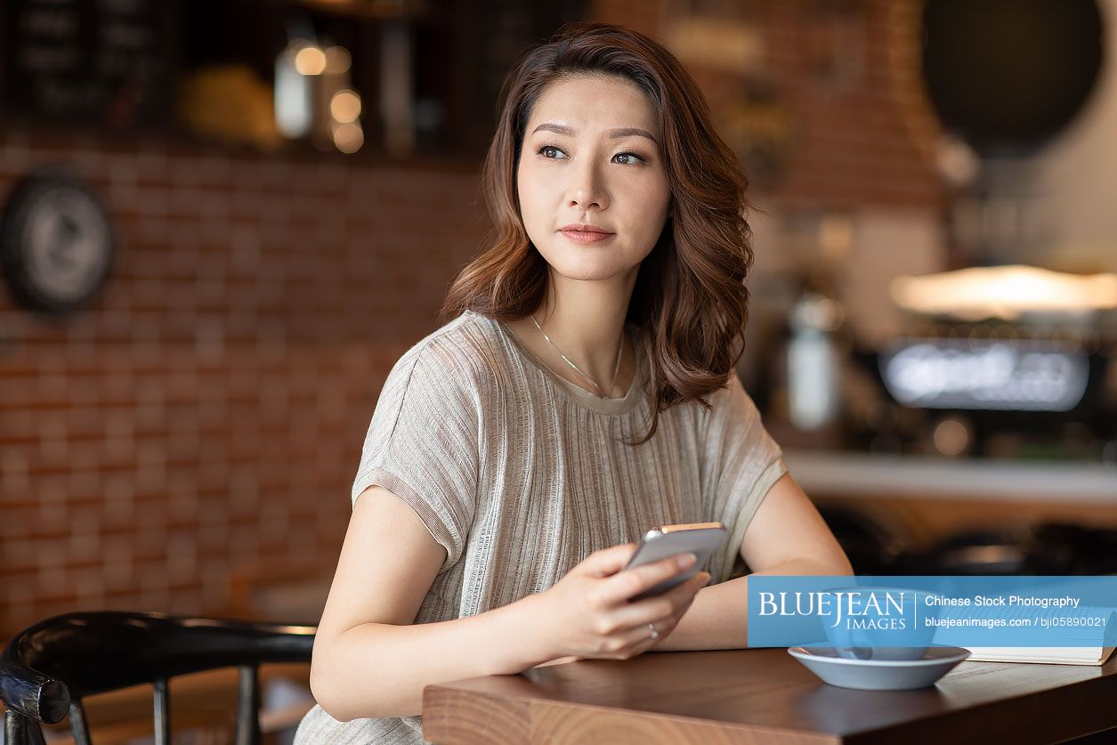 Elegant Chinese woman using smartphone in cafe-High-res stock photo for ...