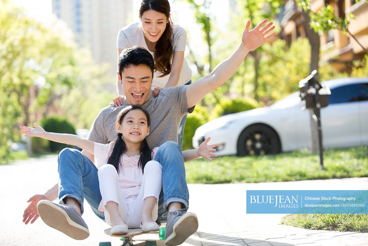 Happy young Chinese family playing with skateboard-High-res stock photo for download