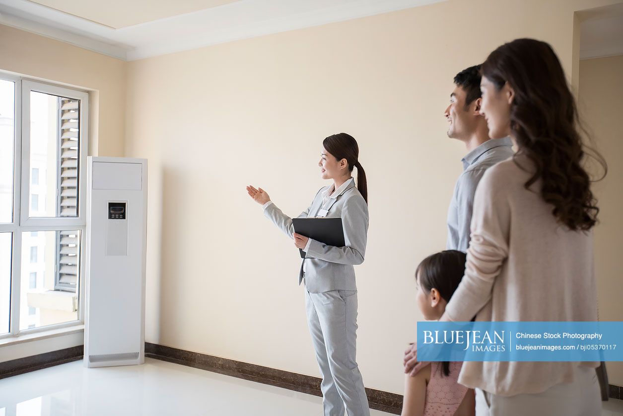 Chinese realtor showing new house to young family-High-res stock photo for download