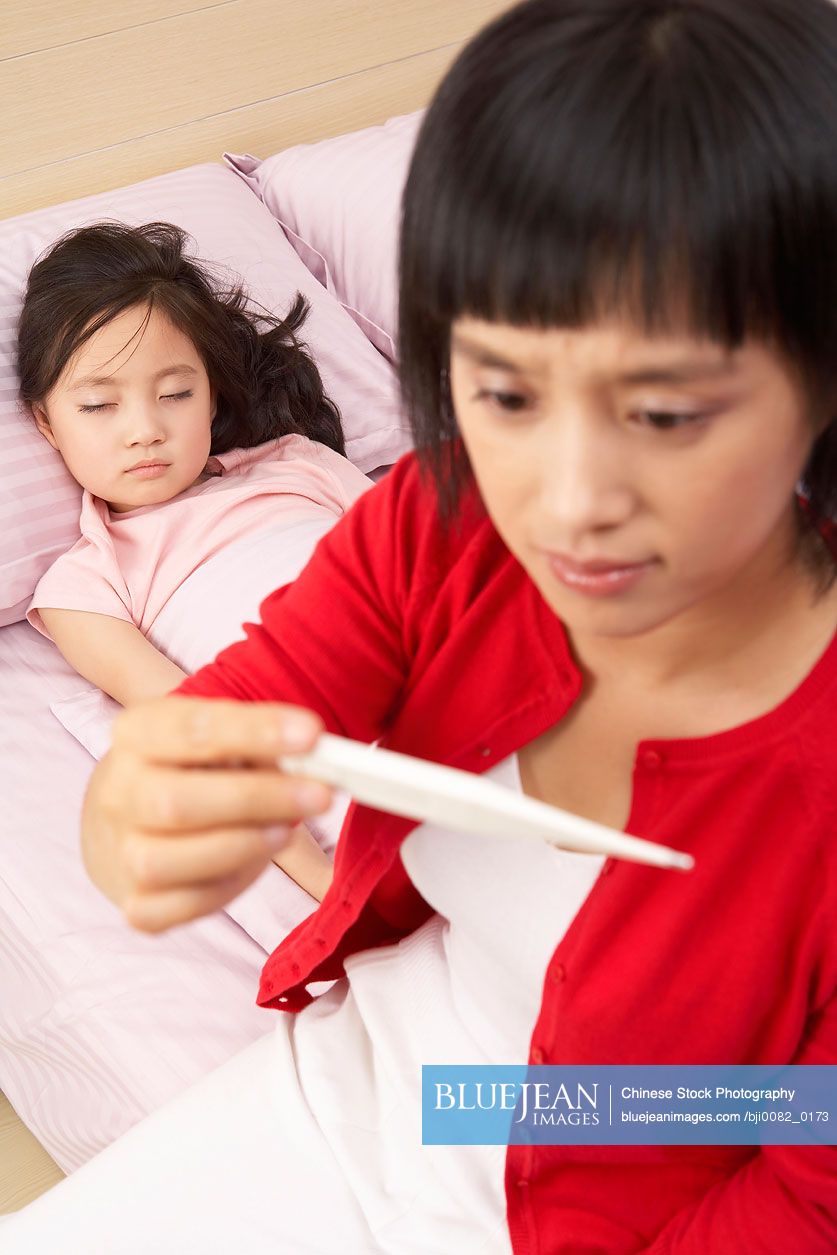 Chinese mother checking sick daughter's temperature-High-res stock photo for download