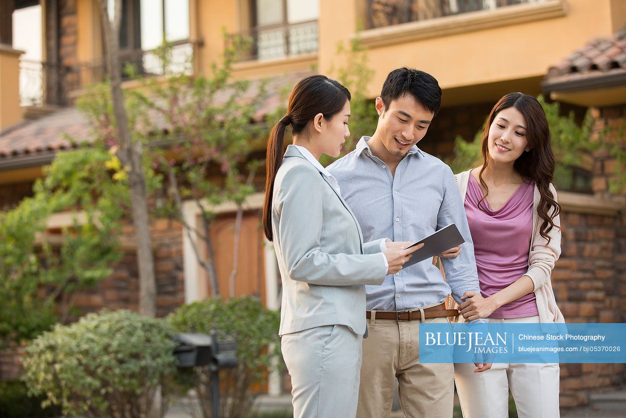 Happy young Chinese couple talking with realtor-High-res stock photo for download