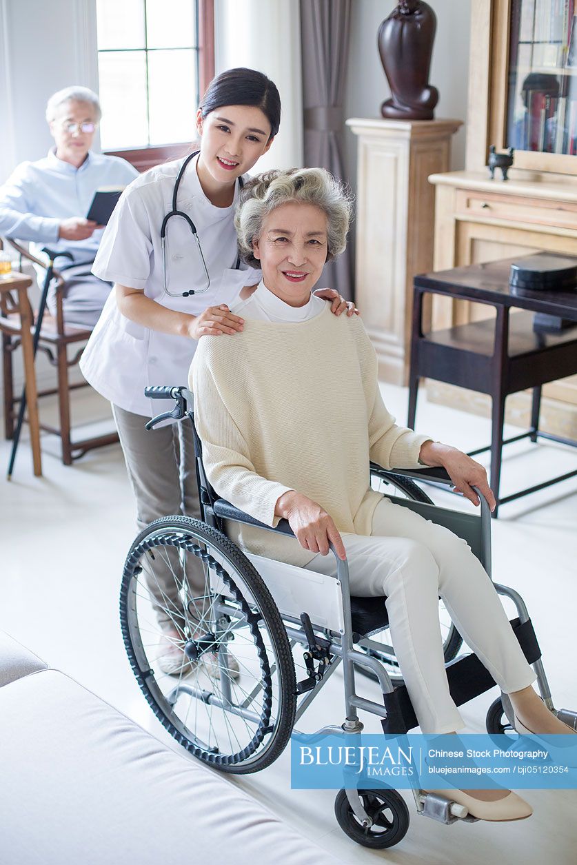 Chinese nursing assistant taking care of senior woman in wheel chair ...