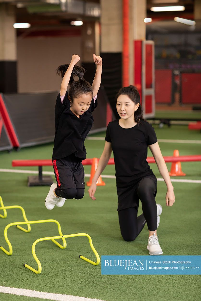 Cute Chinese girl having exercise class with coach in gym-High-res ...