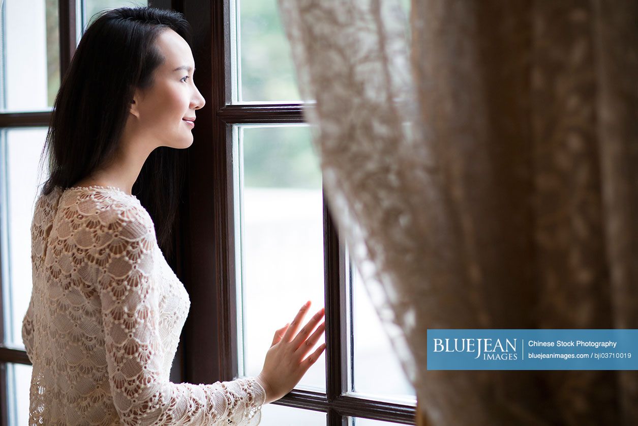 Young Chinese woman looking through window-High-res stock photo for ...
