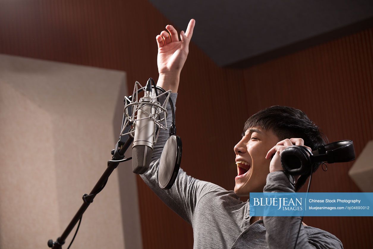 Young Chinese man singing in recording studio-High-res stock photo for download
