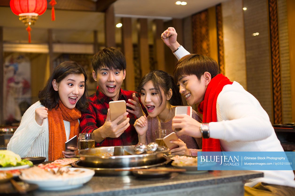 Young Chinese friends grabbing Wechat hongbao with smart phones-High ...