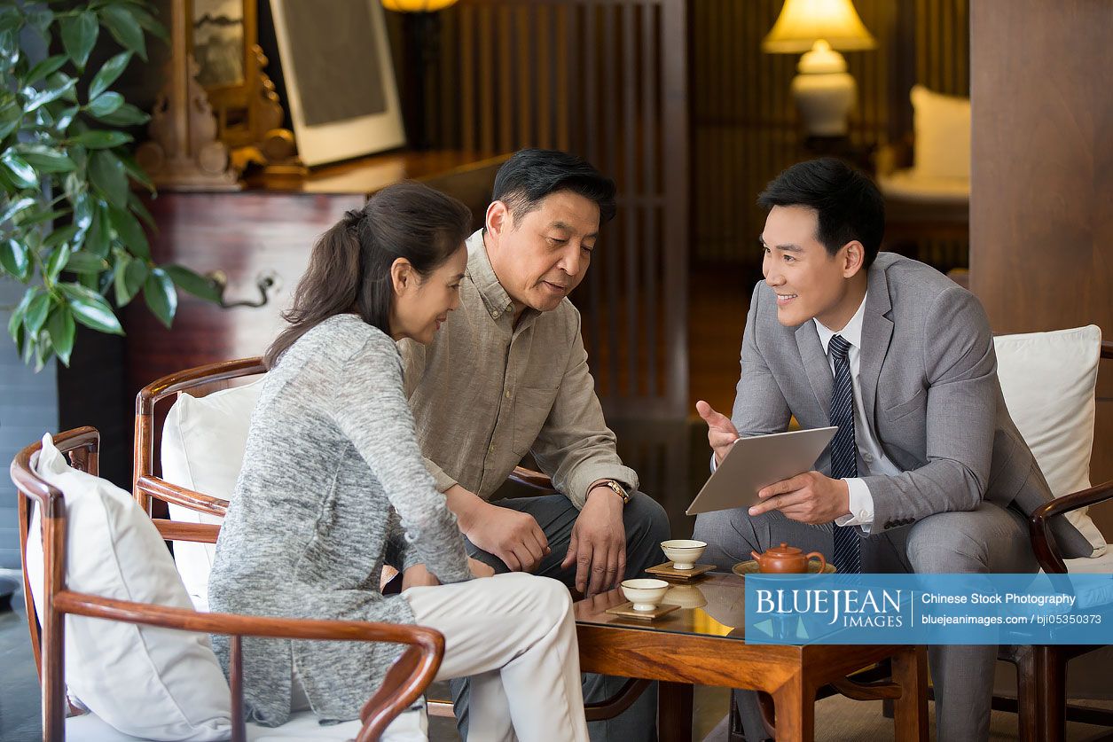 Confident Chinese financial consultant talking with mature couple-High ...