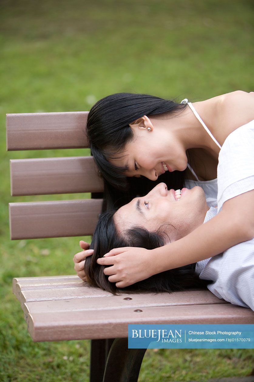 Young Chinese couple lying on bench, outdoors-High-res stock photo for download