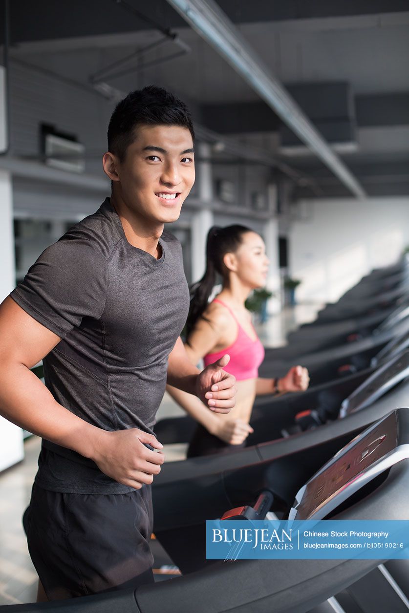Young Chinese couple exercising on treadmills in gym-High-res stock photo for download