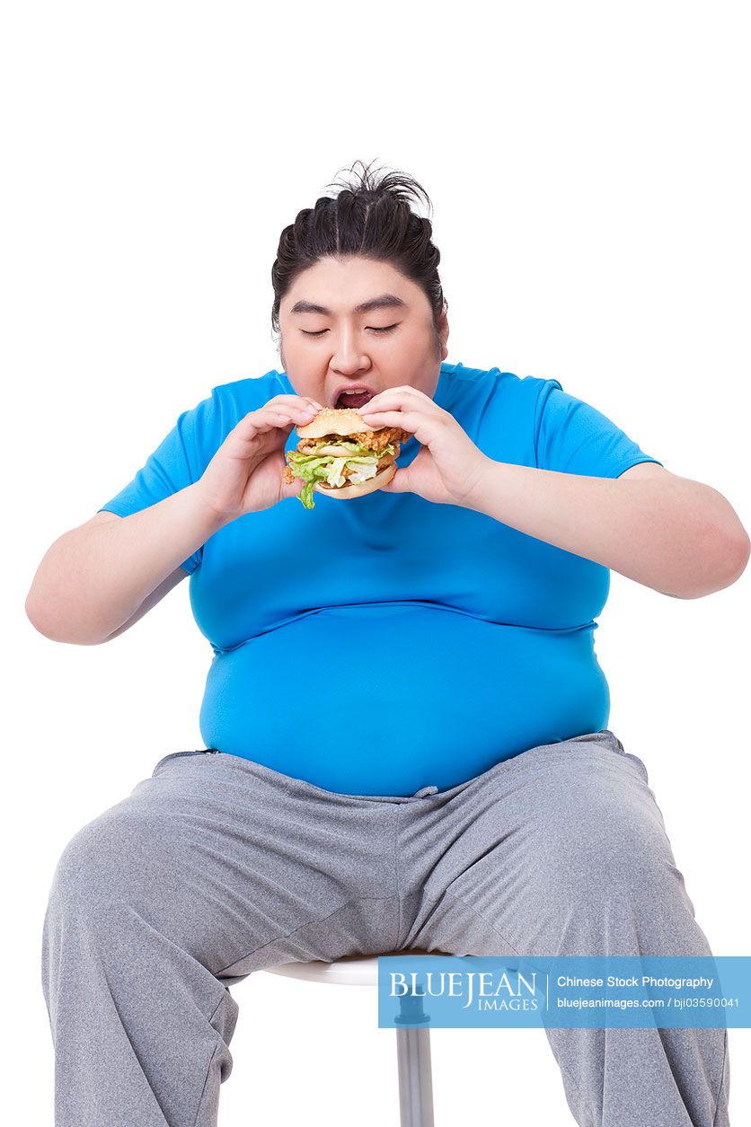 Greedy Chubby Chinese man gobbling a burger-High-res stock photo for download