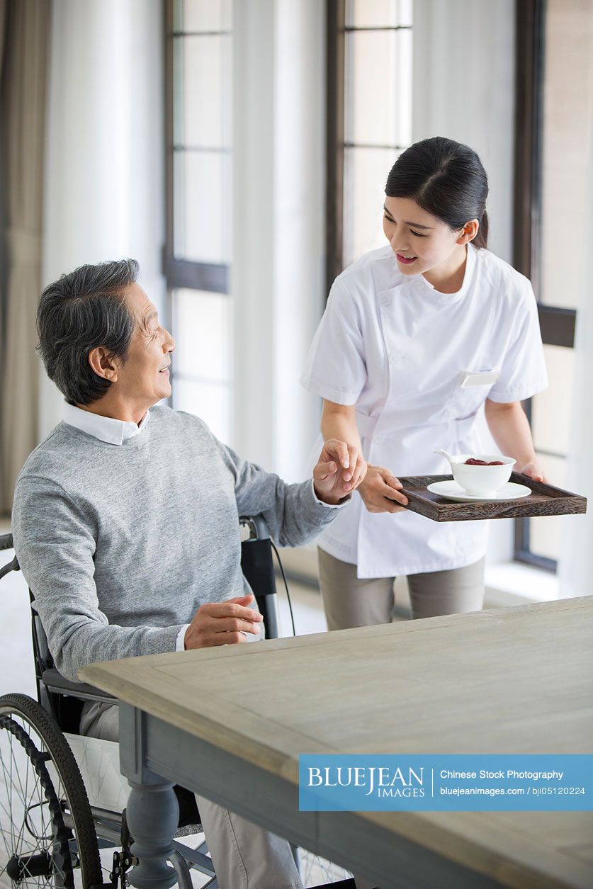 Chinese nursing assistant taking care of senior man in wheel chair-High ...