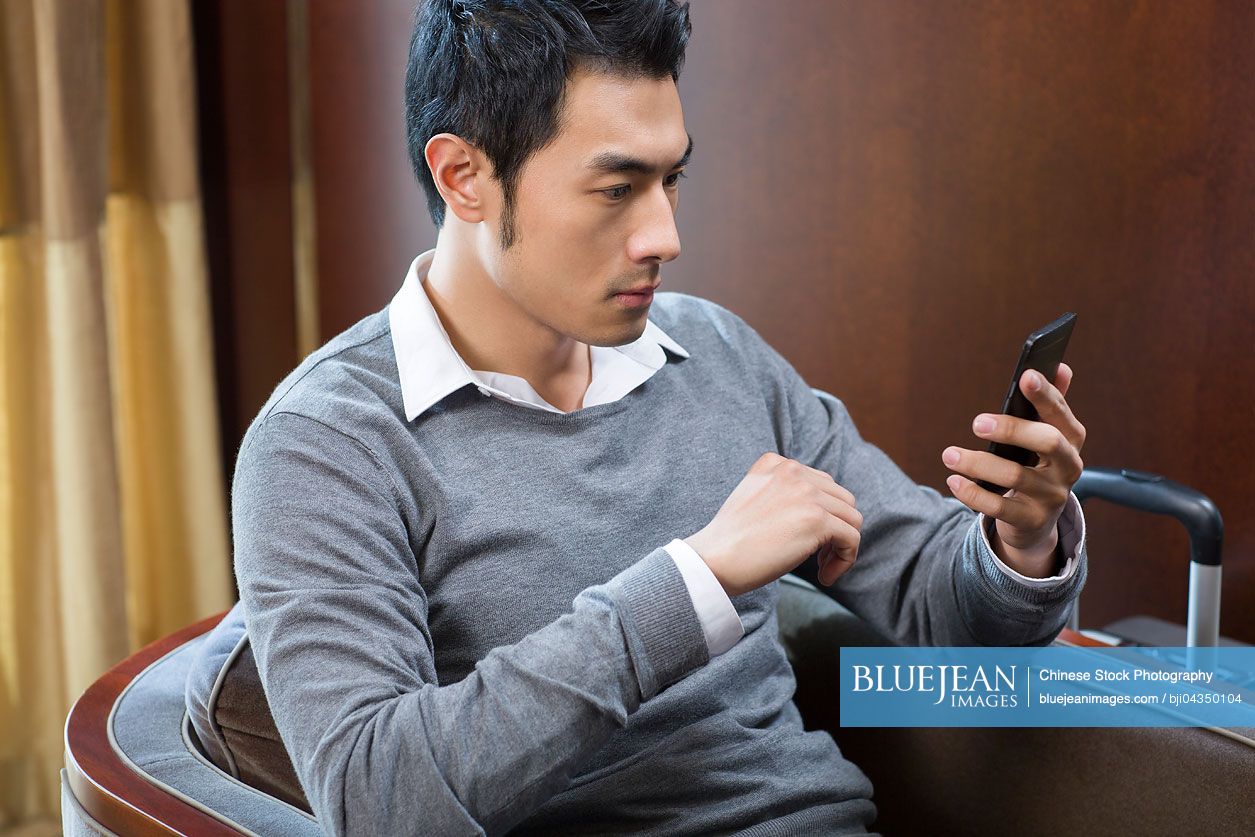 Young Chinese businessman using smart phone in hotel room-High-res ...