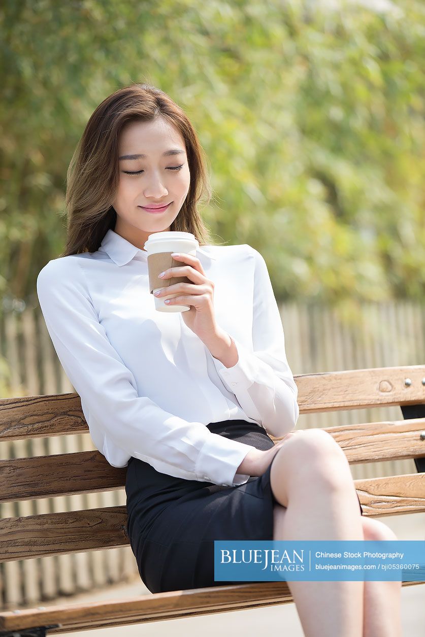 Cheerful young Chinese businesswoman drinking coffee-High-res stock photo for download