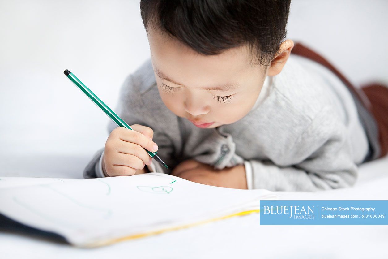 Happy little Chinese boy lying on front and writing-High-res stock ...