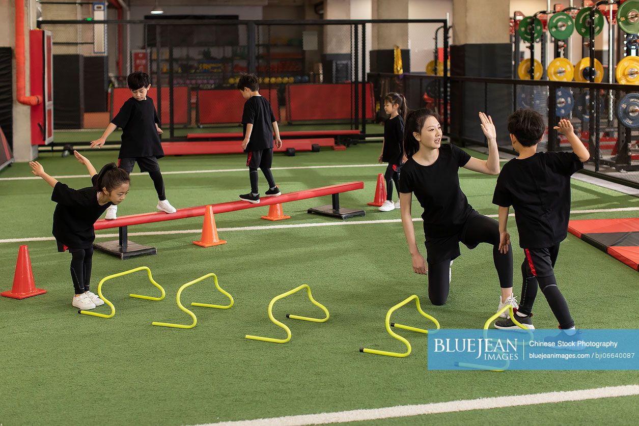 Active Chinese children having exercise class with their coach in gym-High-res stock photo for ...