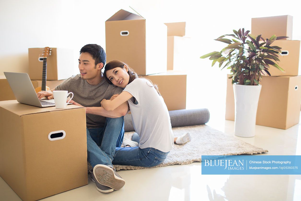 Young Chinese couple using laptop in their new house-High-res stock photo for download