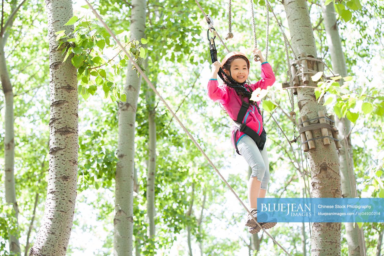 Little Chinese girl playing in tree top adventure park-High-res stock photo for download