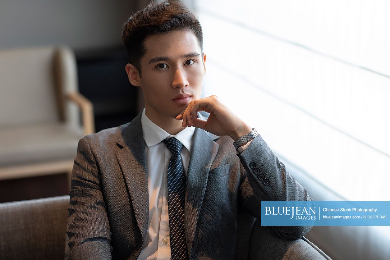 Young Chinese businessman sitting on sofa in hotel room-High-res stock ...