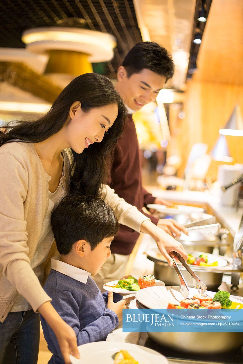 Cheerful young Chinese family taking food from buffet table-High-res ...