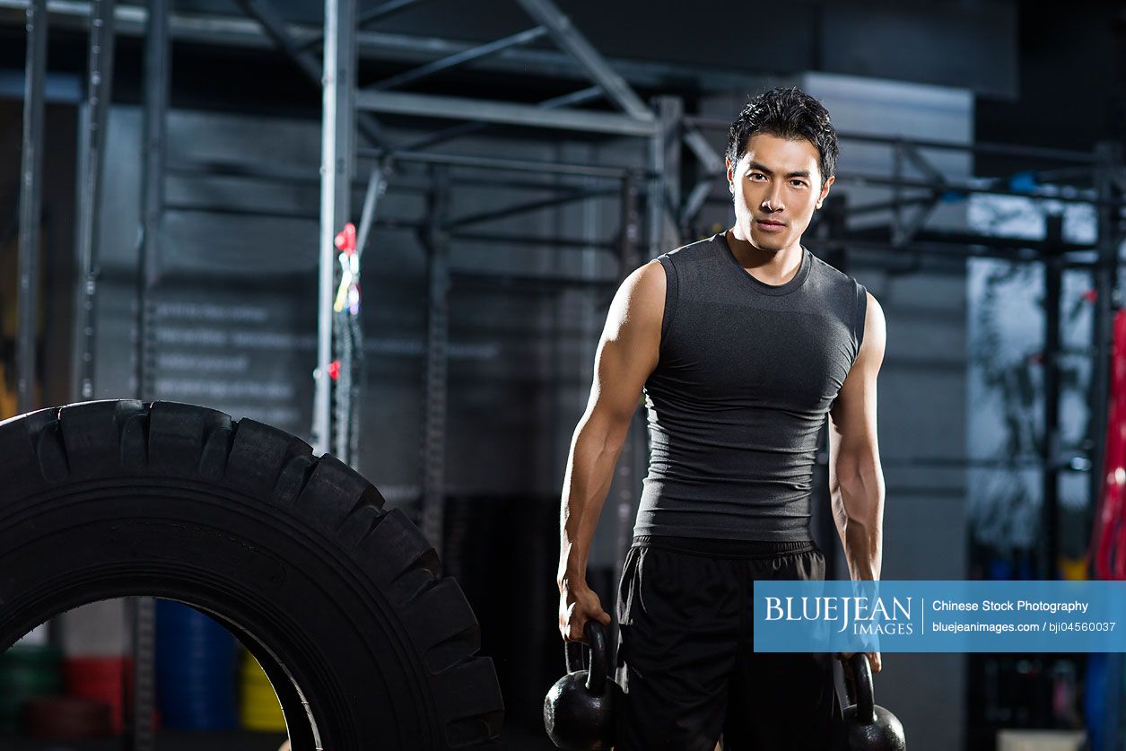 Young Chinese man training with kettlebells in crossfit gym-High-res ...