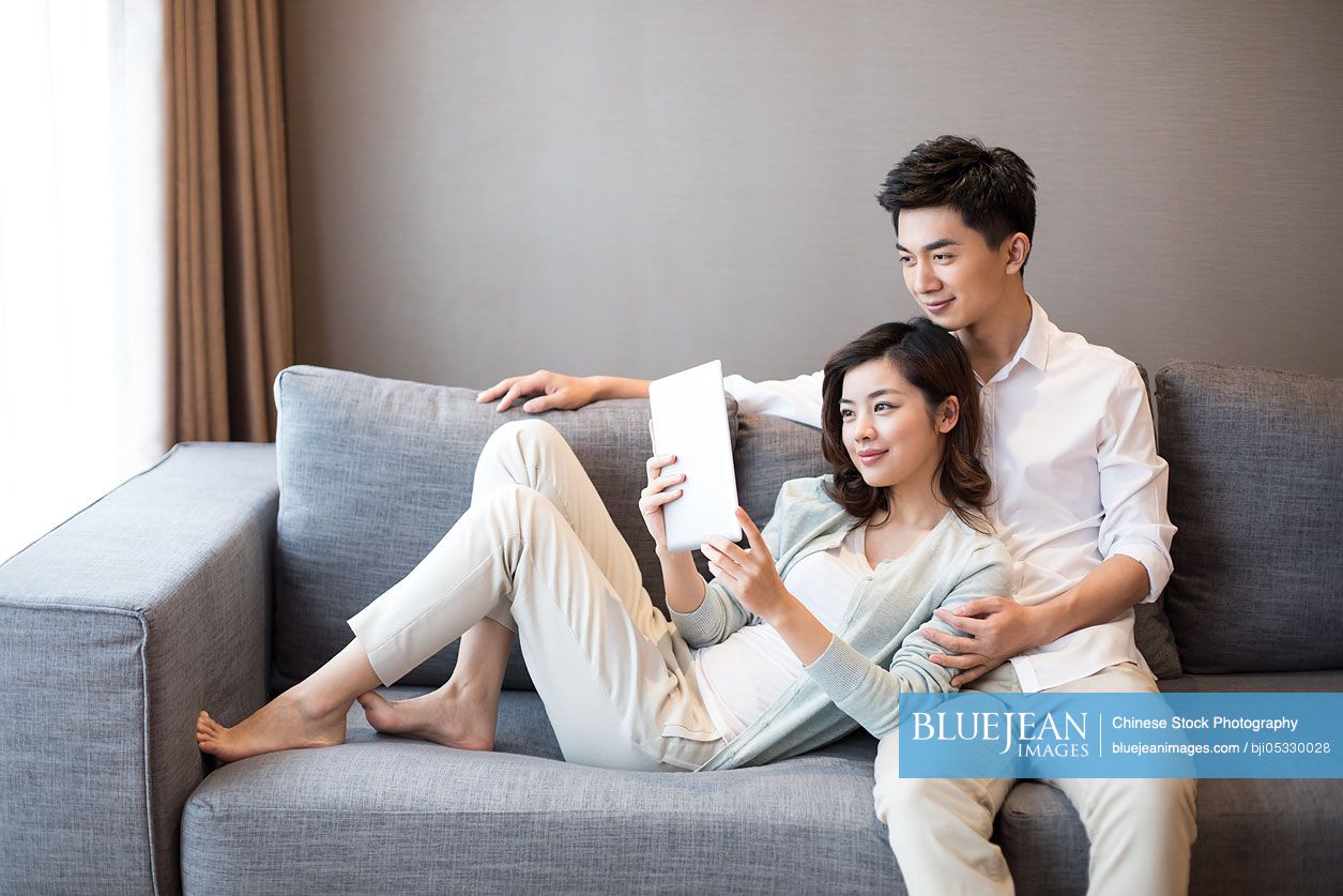 Cheerful young Chinese couple using digital tablet at home-High-res ...