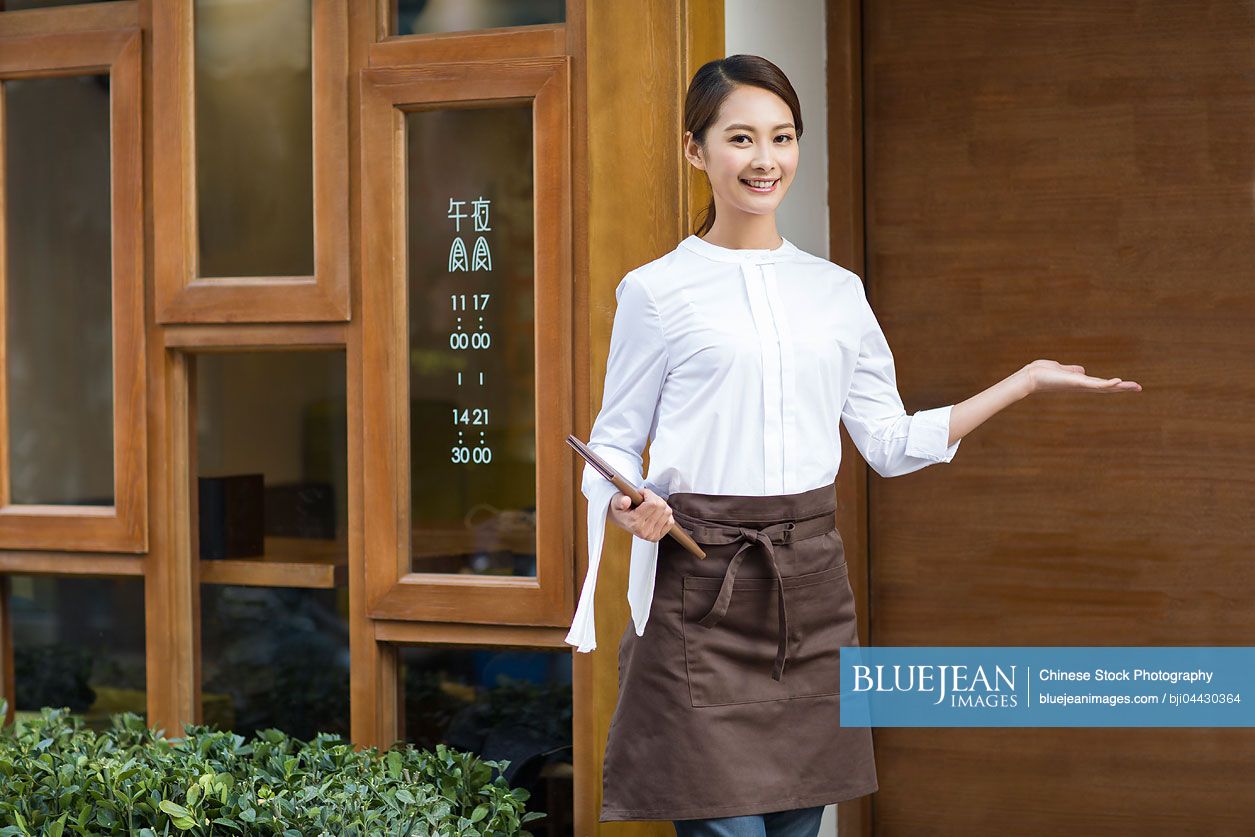 Young Chinese waitress greeting in restaurant doorway-High-res stock ...