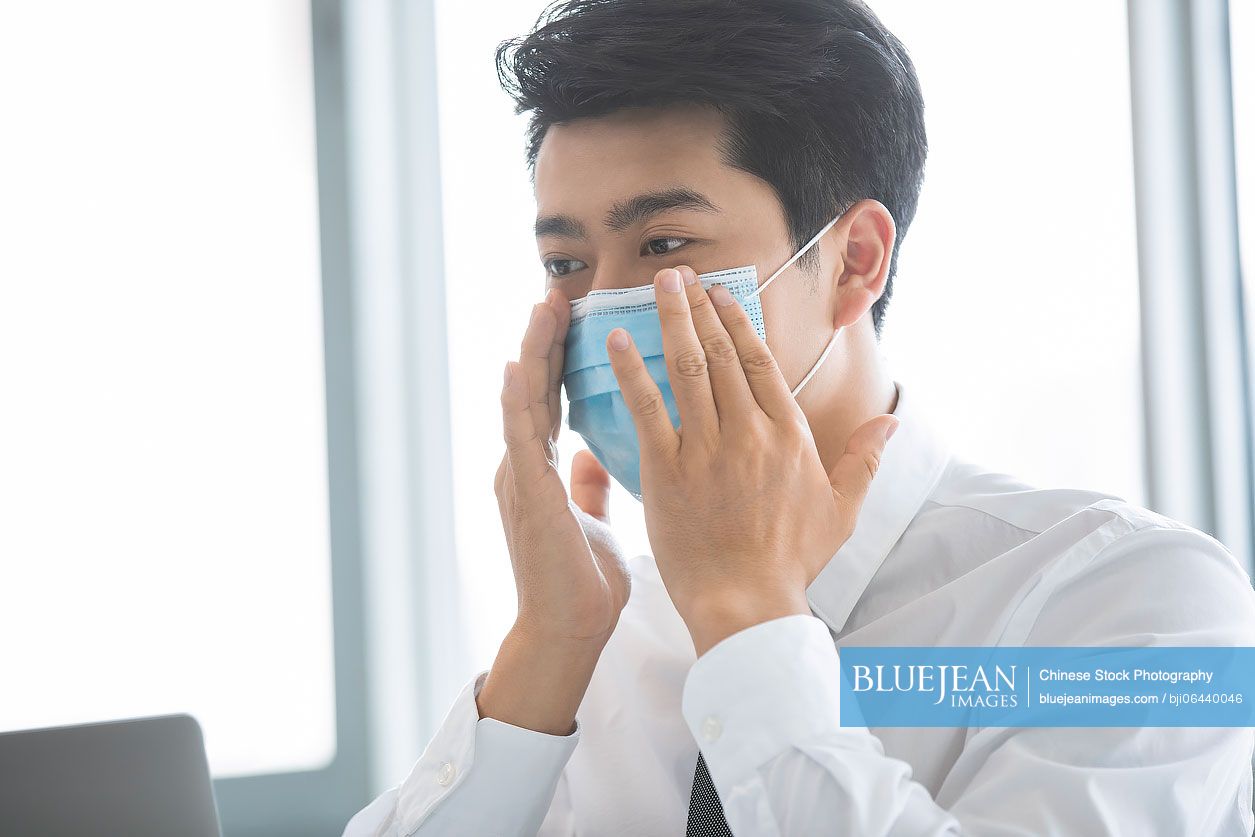 Young Chinese businessman wearing surgical mask in office-High-res ...