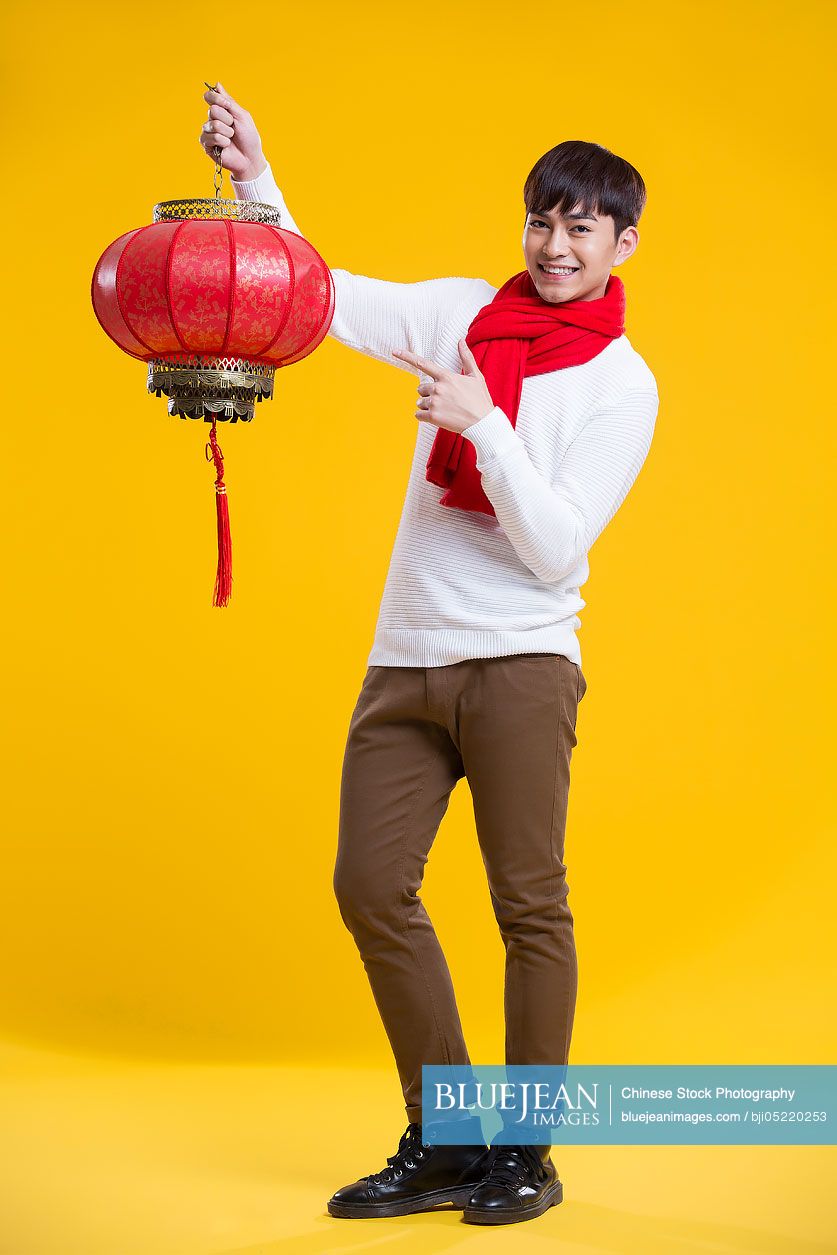 Cheerful young man celebrating Chinese new year with traditional ...