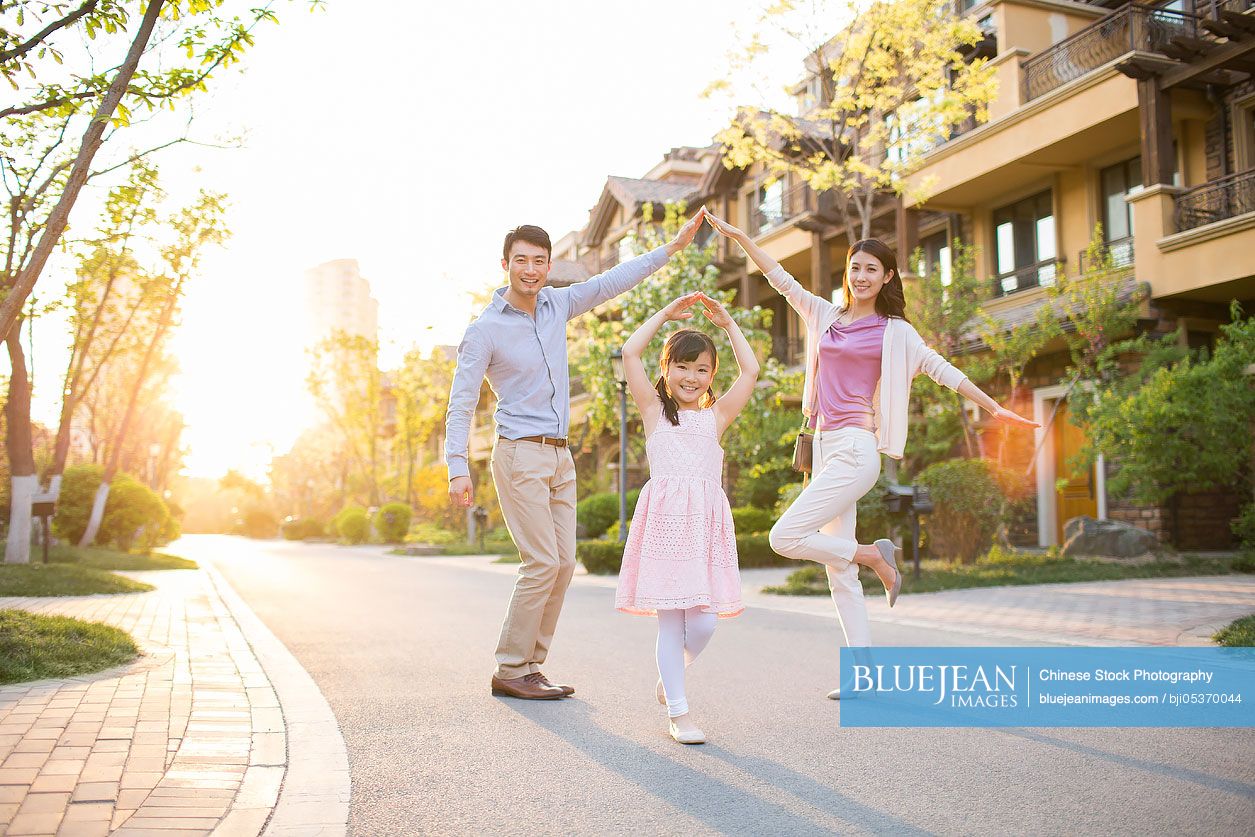 Happy young Chinese family standing in front of their new house-High ...