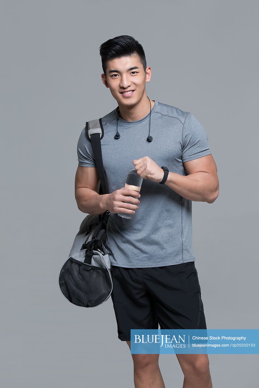 Cheerful young Chinese male athlete holding a bottle of water-High-res stock photo for download