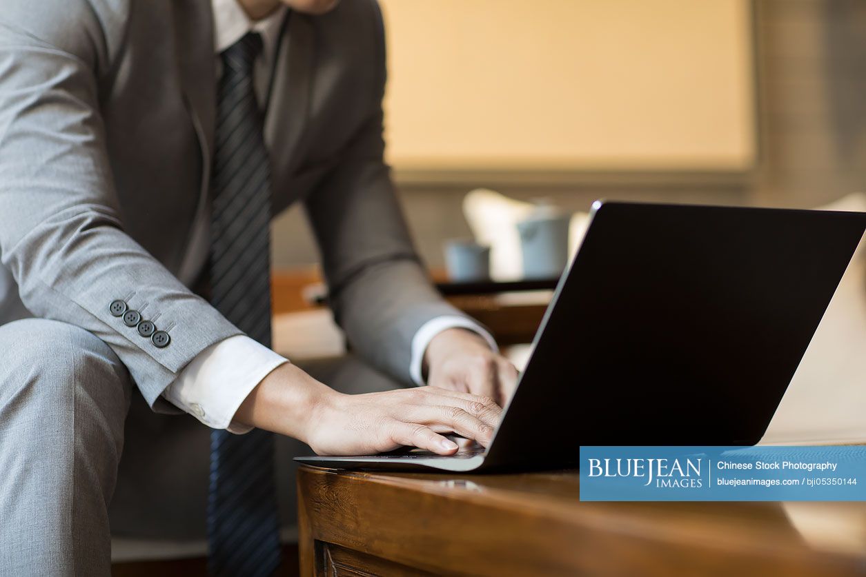 Confident Chinese businessman using laptop-High-res stock photo for download