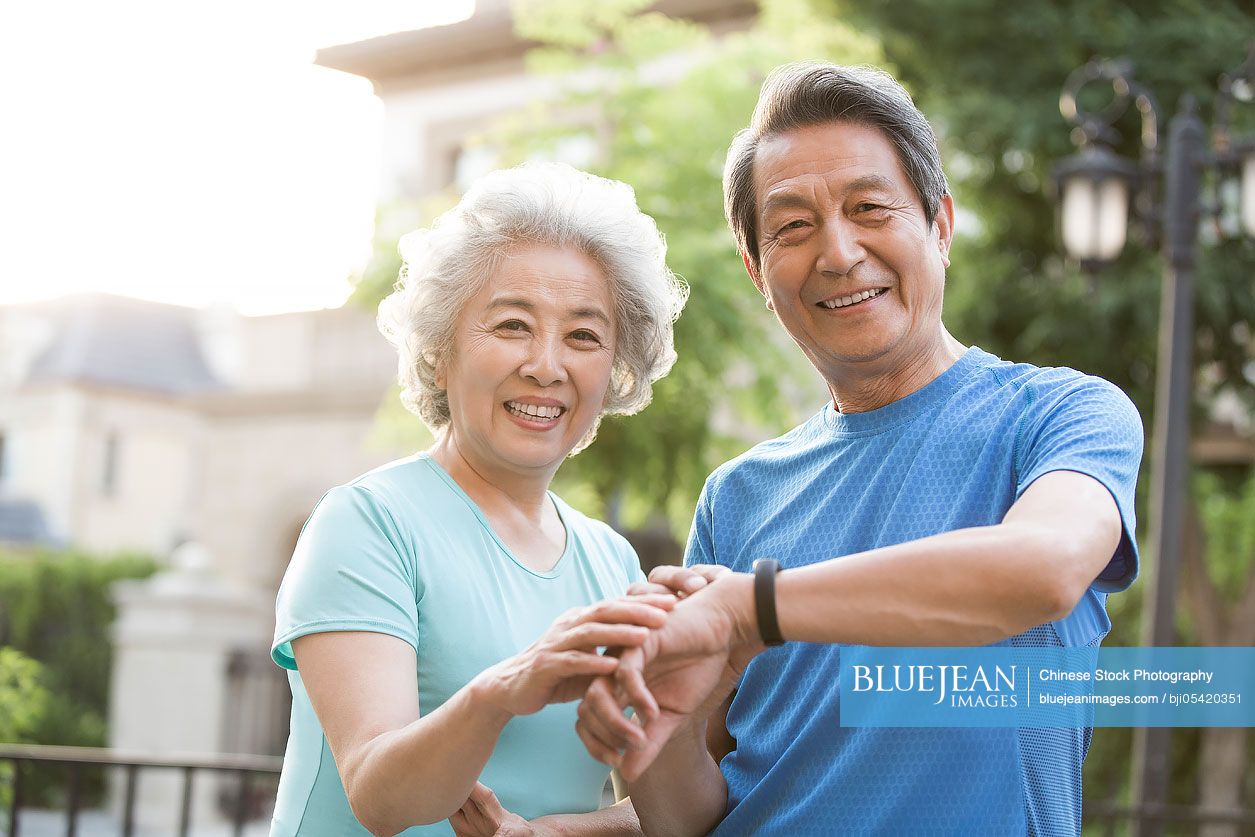 Cheerful senior Chinese couple checking smart watch-High-res stock photo for download