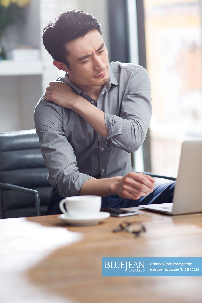Tired young Chinese man working in office-High-res stock photo for download