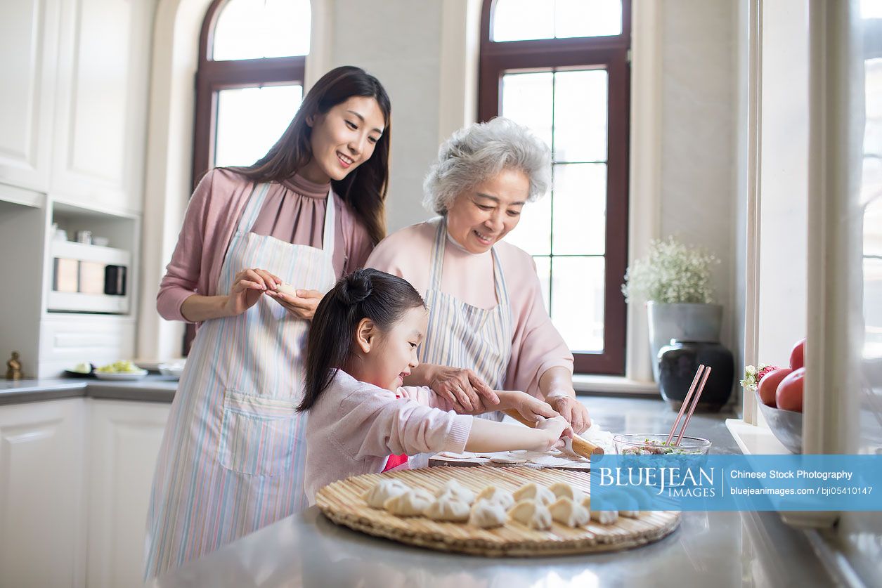 Cheerful Chinese family making dumplings in kitchen-High-res stock ...