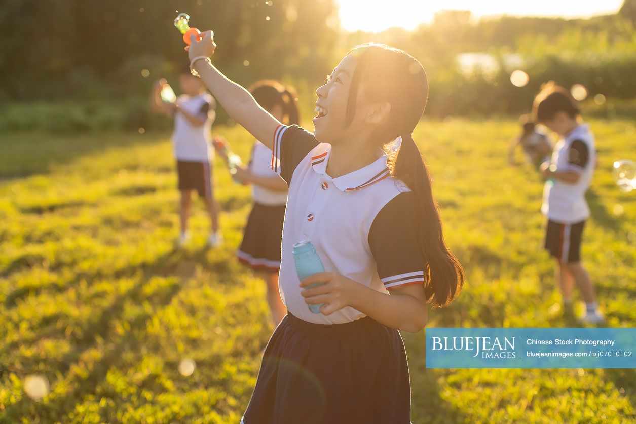 Cheerful Chinese school children blowing bubbles on meadow-High-res ...