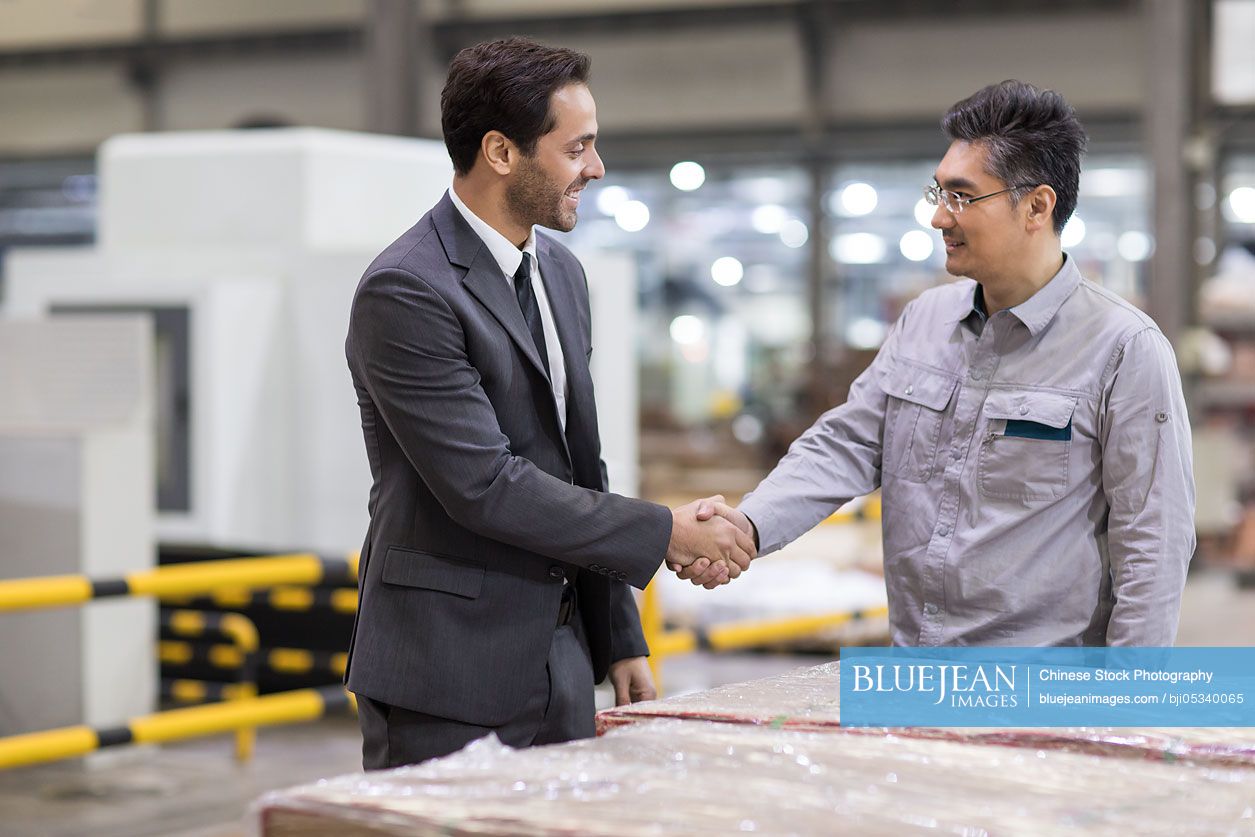 Businessman and engineer shaking hands in the factory-High-res stock photo for download