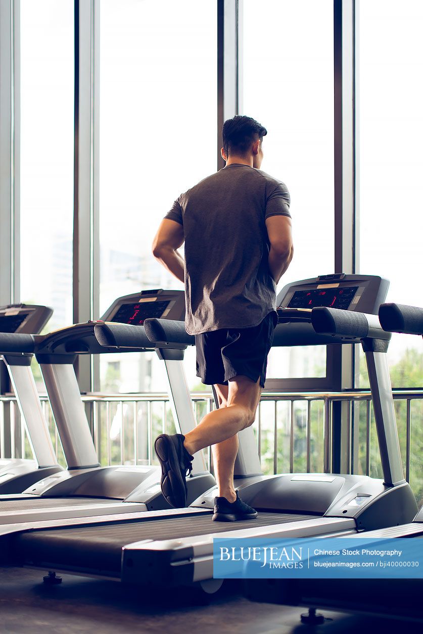 Young Chinese man running on treadmill at gym-High-res stock photo for ...